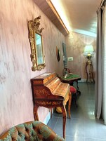 Um quarto com um piano, um sofá, um espelho e uma luminária.