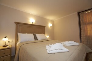 Quarto de hotel com cama, abajures e mesa de cabeceira.