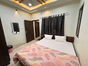 Quarto com cama, cortinas, espelho e porta.