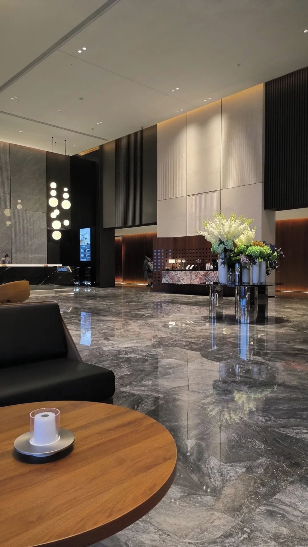 Um lobby moderno com balcão de recepção, área de estar e um arranjo floral decorativo.