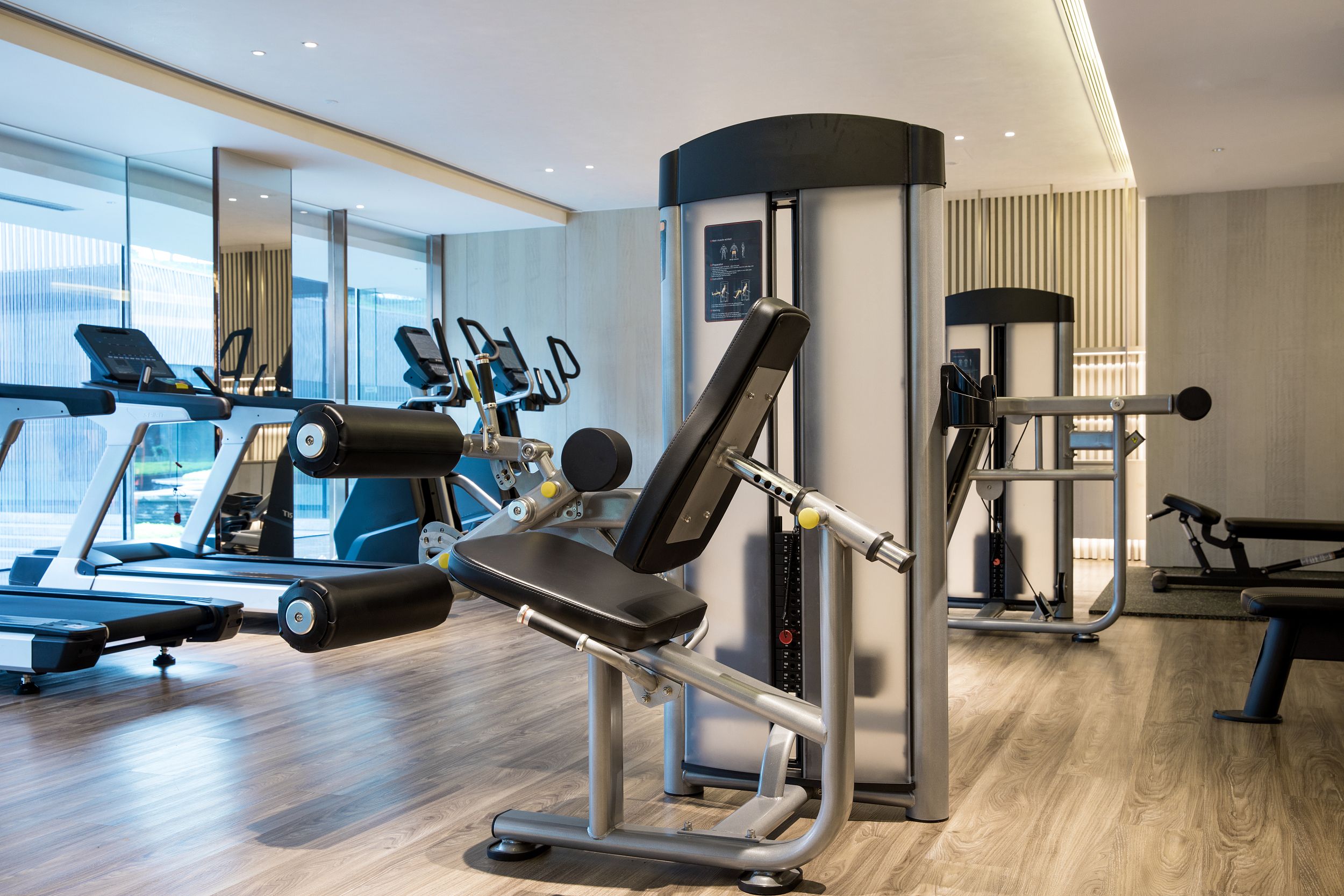 Academia moderna com diversos equipamentos de ginástica, incluindo um banco de musculação e um remo.