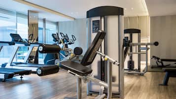 Academia moderna com diversos equipamentos de ginástica, incluindo um banco de musculação e um remo.