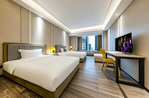 Quarto de hotel com duas camas, uma escrivaninha, uma cadeira e uma televisão.