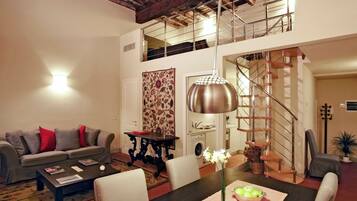 Uma sala de estar ampla, com teto alto, escada e um espaço de jantar com mesa e cadeiras.