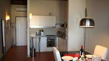 Cozinha compacta com área de jantar, incluindo mesa para dois, com garrafa de vinho e copos.