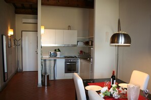 Cozinha compacta com área de jantar, incluindo mesa para dois, com garrafa de vinho e copos.