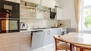 Cozinha moderna com eletrodomésticos embutidos, área de refeições com mesa de madeira e vista para o verde lá fora.
