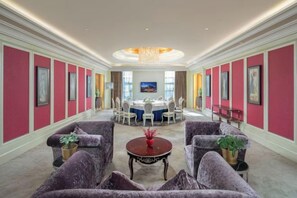 Um quarto amplo com uma mesa de jantar central, rodeada por cadeiras, e mobiliado com sofás e uma mesa de centro.