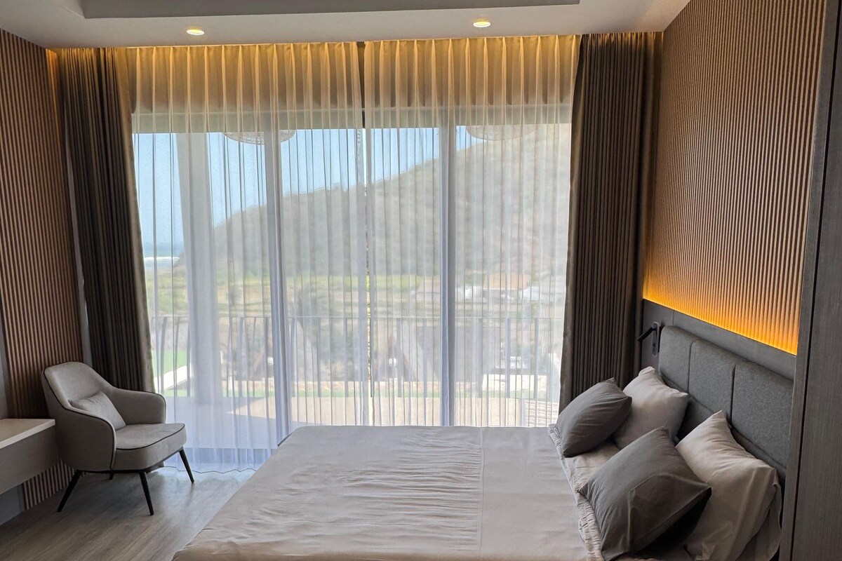 Quarto moderno com cama grande, escrivaninha e uma cadeira.