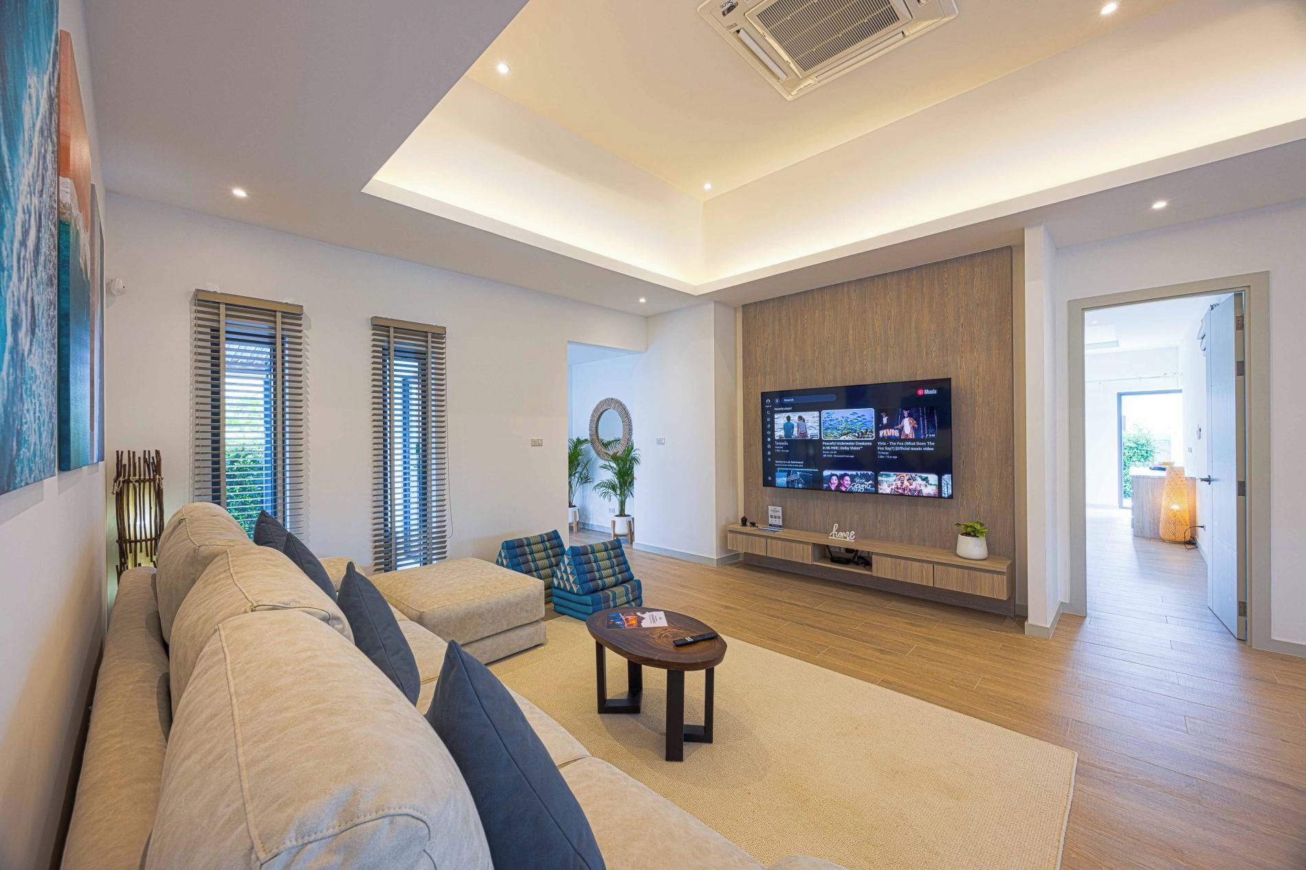 Uma sala de estar moderna com sofá, mesa de centro e uma TV de tela plana na parede.