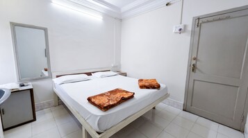 Quarto de hotel com cama, mesa de cabeceira, espelho, guarda-roupa e banheiro com pia.