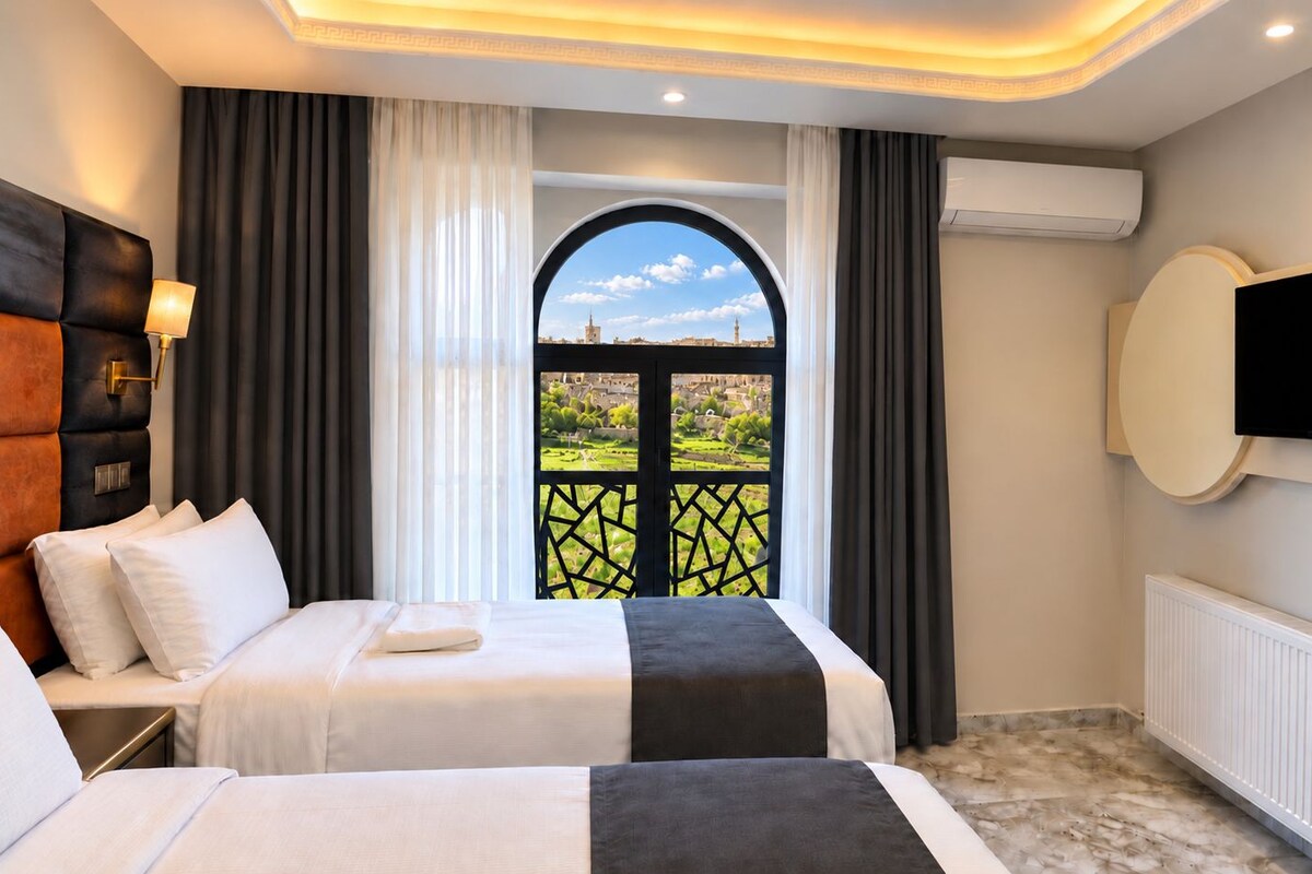 Quarto de hotel com cama, televisão, ar condicionado e janela com vista para a cidade.