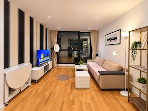 Uma sala de estar moderna com televisão de tela plana, sofá, mesa de centro e abajur.