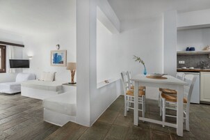 Um espaço de estar moderno e minimalista, com sofá, mesa de jantar e área de cozinha.