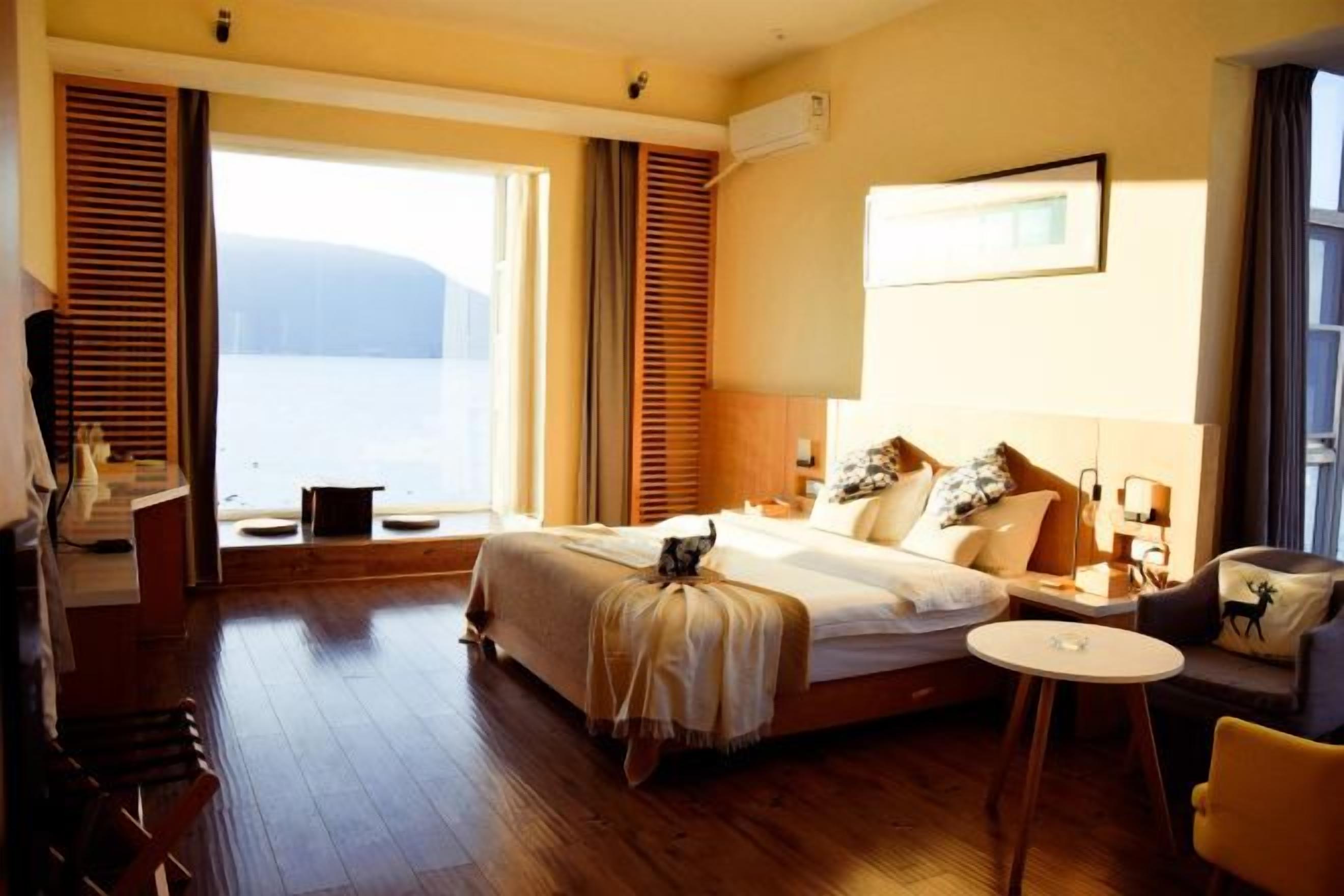 Quarto de hotel com cama, mesa de cabeceira e vista para o mar.