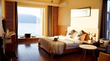 Quarto de hotel com cama, mesa de cabeceira e vista para o mar.
