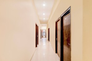 Corredor com portas em ambos os lados, conduzindo a um quarto com janela.