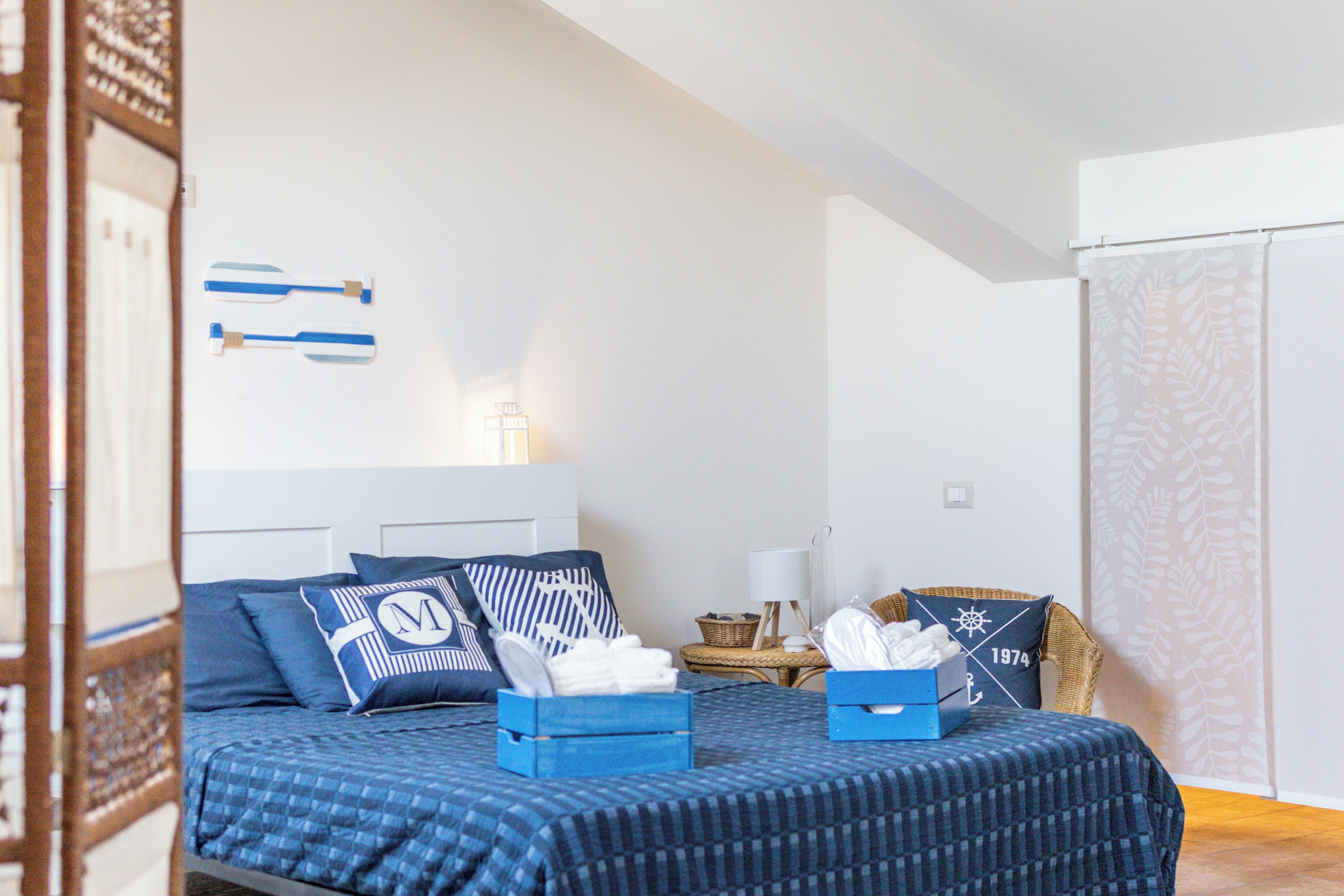 Quarto com cama, travesseiros, mesa de cabeceira, luminária e janela.
