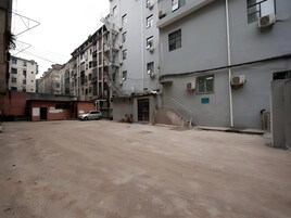 Um edifício com vários andares e uma área de estacionamento na frente.