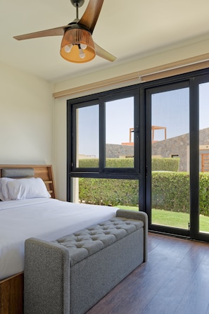 Quarto com cama, um banquinho e ventilador de teto.