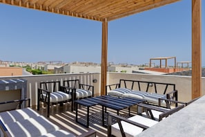 Terraço no telhado com mobiliário para área externa, pérgola e vista da paisagem urbana.