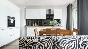 Cozinha moderna com armários brancos, bancada preta e área de refeições com sofá estampado em zebra.