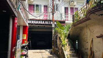 Uma rua estreita com um edifício identificado como 'DEVANGA RETREAT' e uma scooter estacionada.