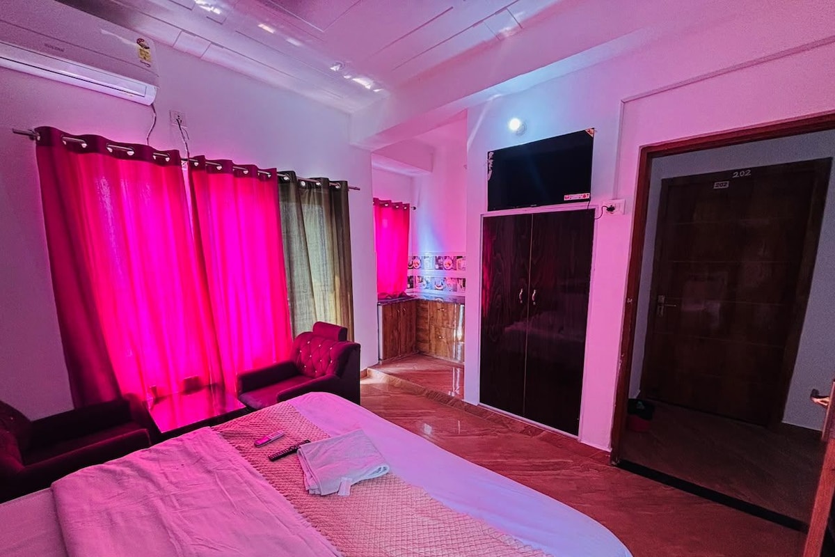 Quarto com cama, cortinas, televisão e guarda-roupa.