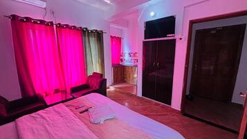 Quarto com cama, cortinas, televisão e guarda-roupa.