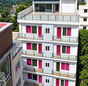 Um edifício residencial de vários andares com varandas, janelas amplas e vista para uma paisagem montanhosa.