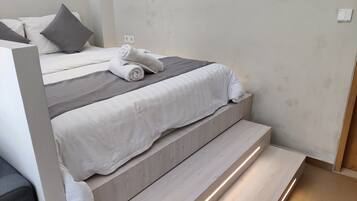 Quarto de hotel moderno com uma cama, um conjunto de degraus que levam à cama e uma luminária fixada na parede.