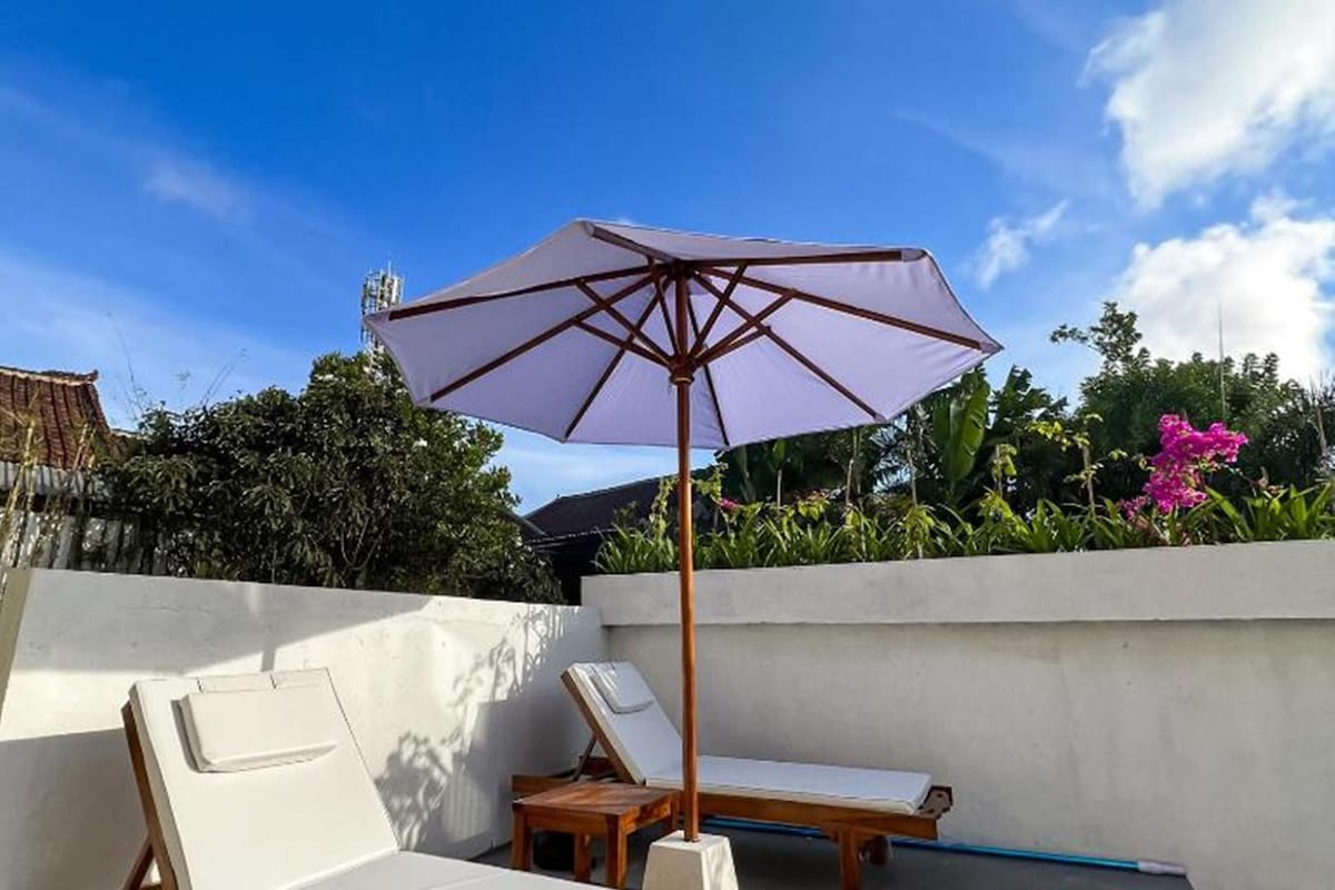 Terraço no telhado com duas poltronas de madeira e um grande guarda-sol.
