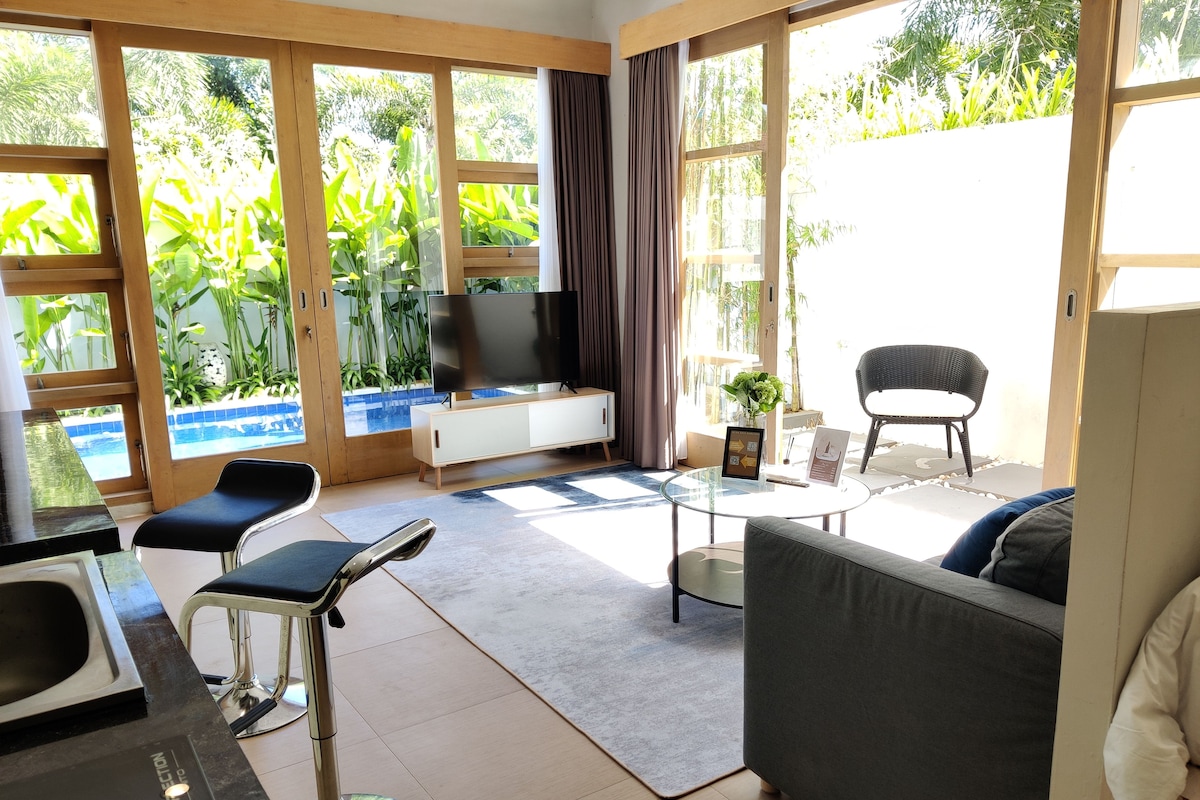 Sala moderna com TV, assentos e vista para uma piscina.