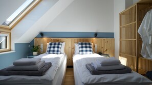 Quarto com duas camas, um claraboia, guarda-roupa de madeira e uma pequena mesa com uma planta.