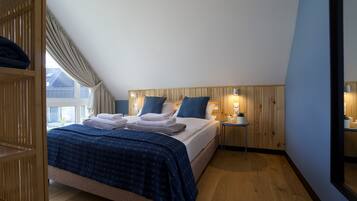 Quarto com cama, mesas de cabeceira e uma janela.