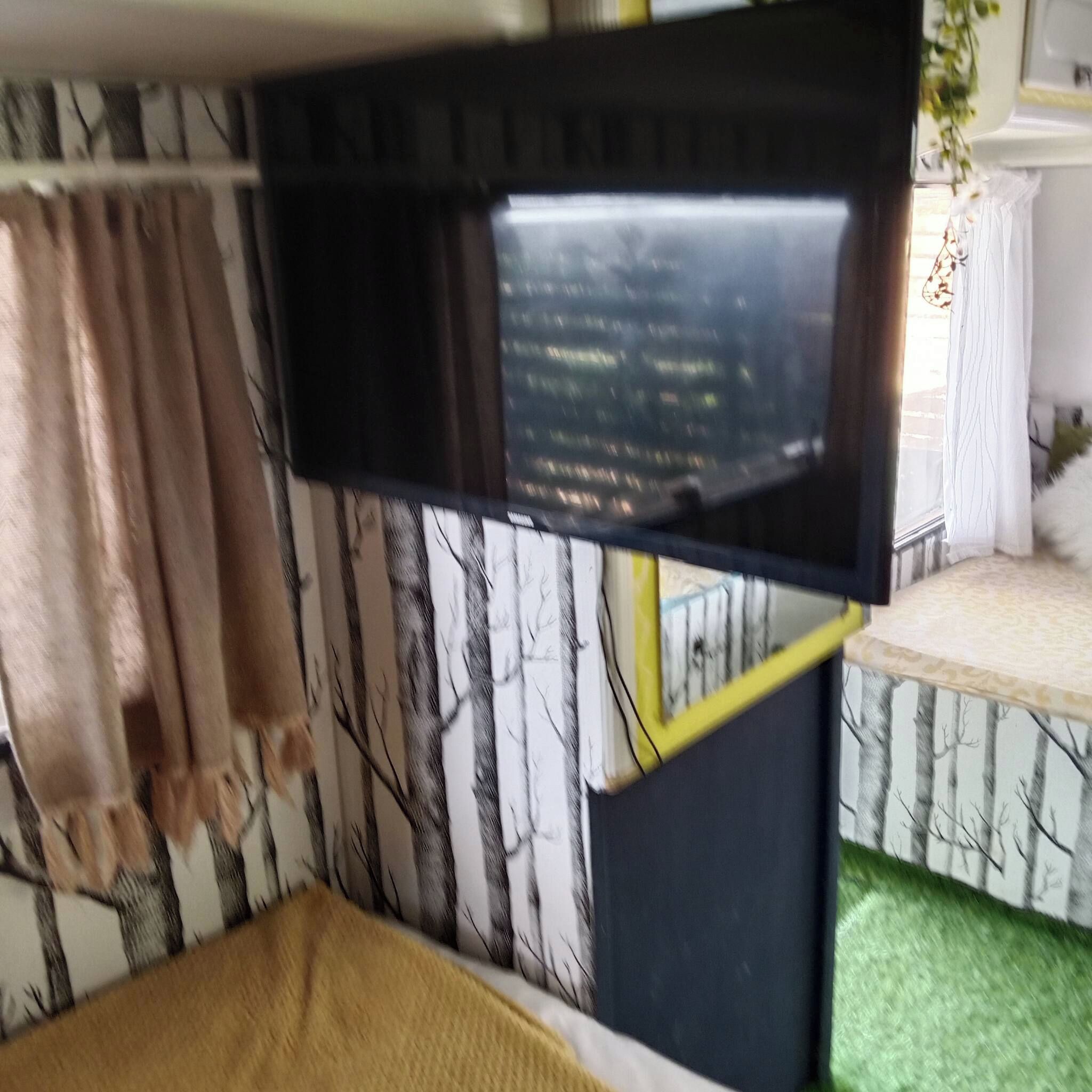 Quarto com cama, janela com cortinas e parede com padrão de árvore.