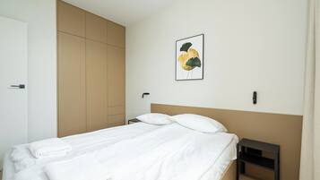 Quarto com cama, mesa de cabeceira, guarda-roupa e um quadro na parede.