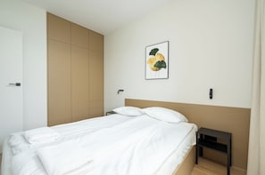 Quarto com cama, mesa de cabeceira, guarda-roupa e um quadro na parede.