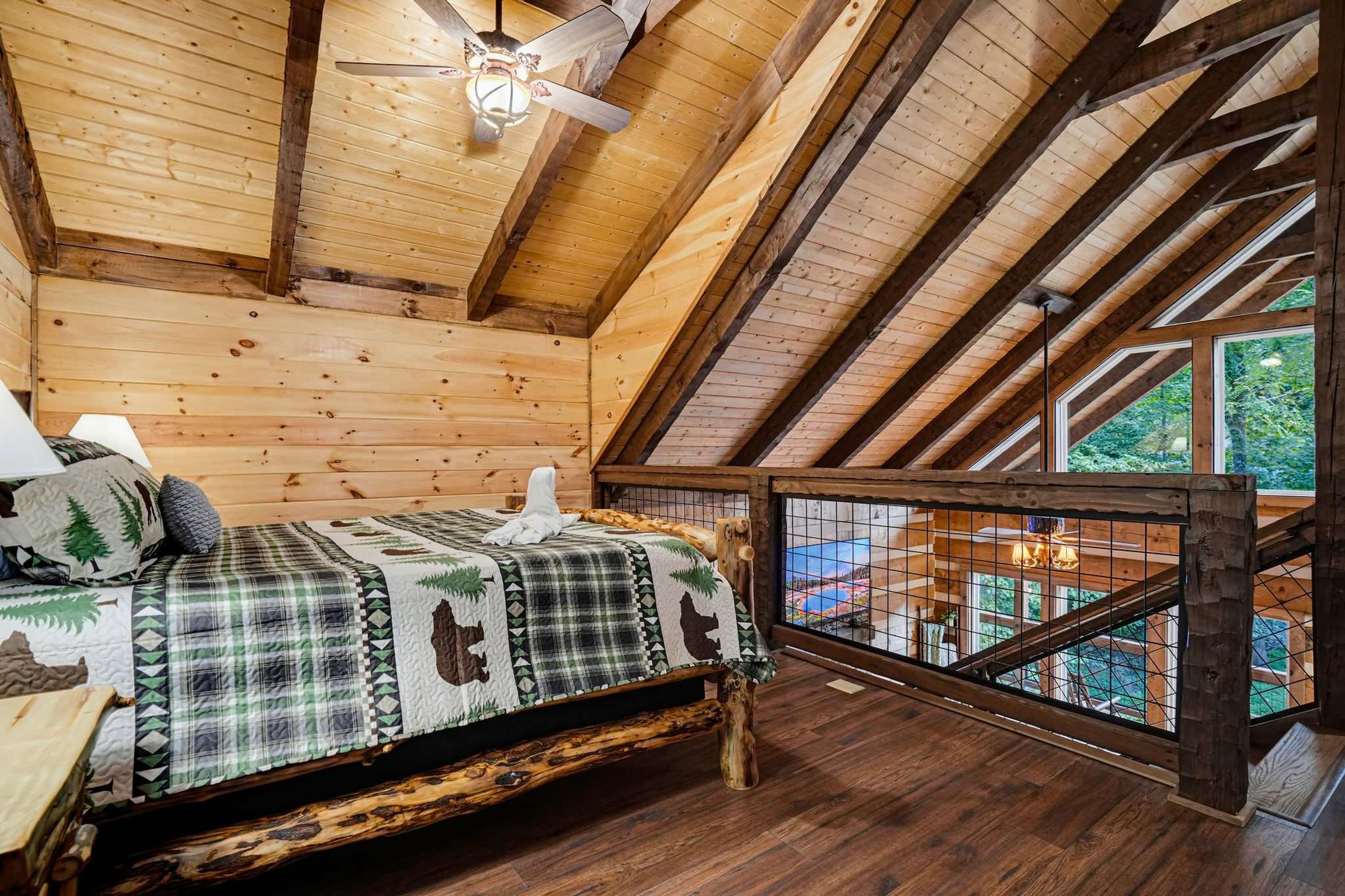 Quarto de cabana aconchegante com teto de madeira, cama com colcha xadrez e vista para um deck de madeira lá fora.