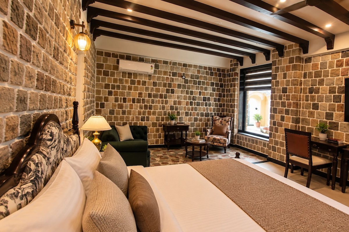 Quarto com parede de pedra, cama, televisão e janela.