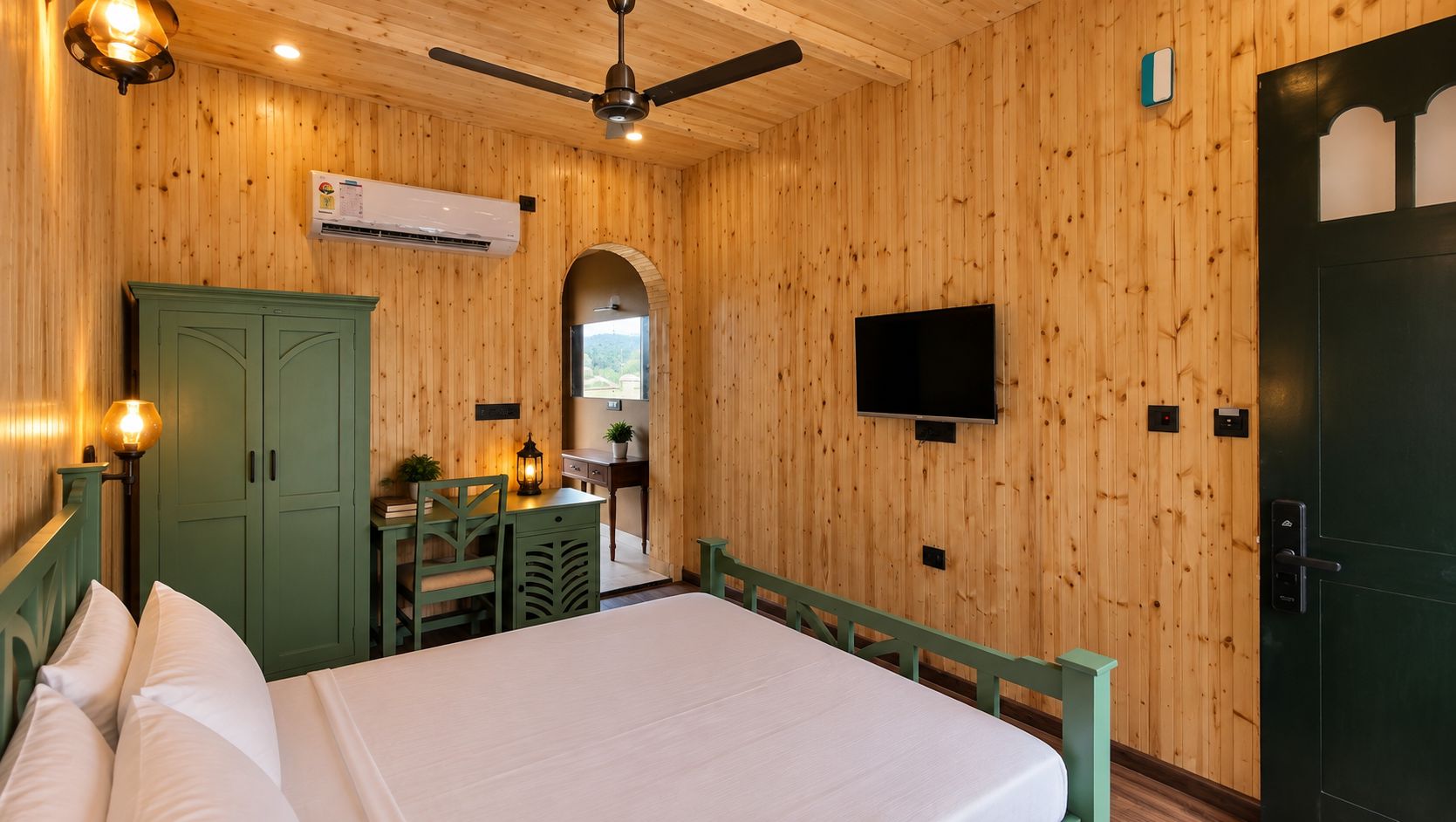 Quarto com cama, escrivaninha, cadeira, televisão e porta.