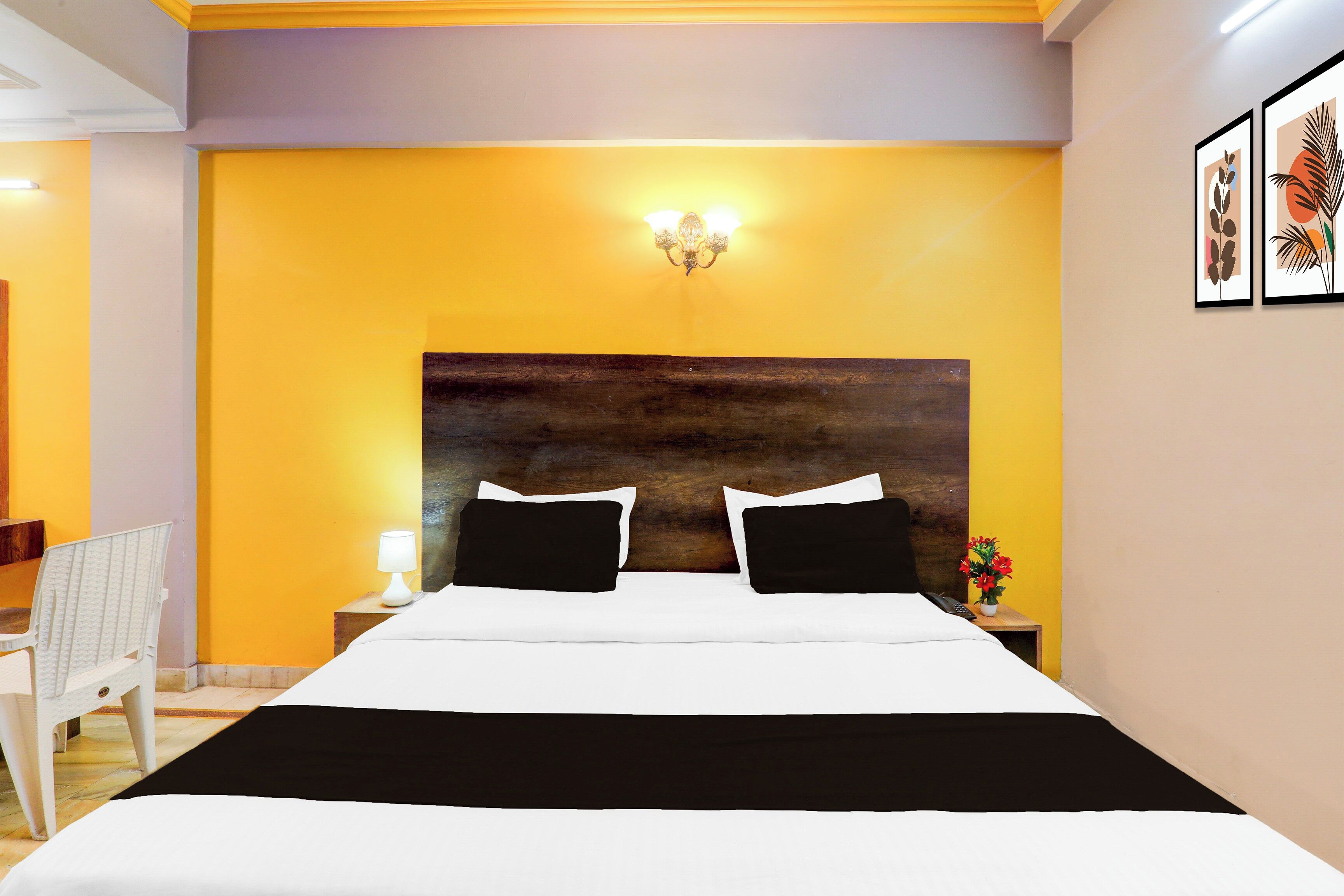 Quarto de hotel com uma cama grande, mesa de cabeceira com abajur, uma cadeira e luminária na parede.