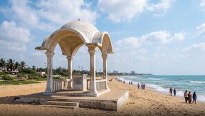 Uma praia com um monumento histórico, arcos e uma placa.