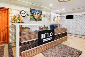 Bancada de recepção de hotel com uma placa indicando 'HOTELO Company-Serviced'.