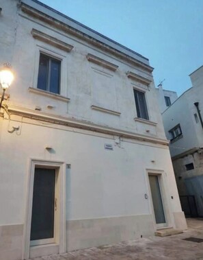 Um edifício de dois andares com fachada plana, duas janelas no andar térreo e uma porta.