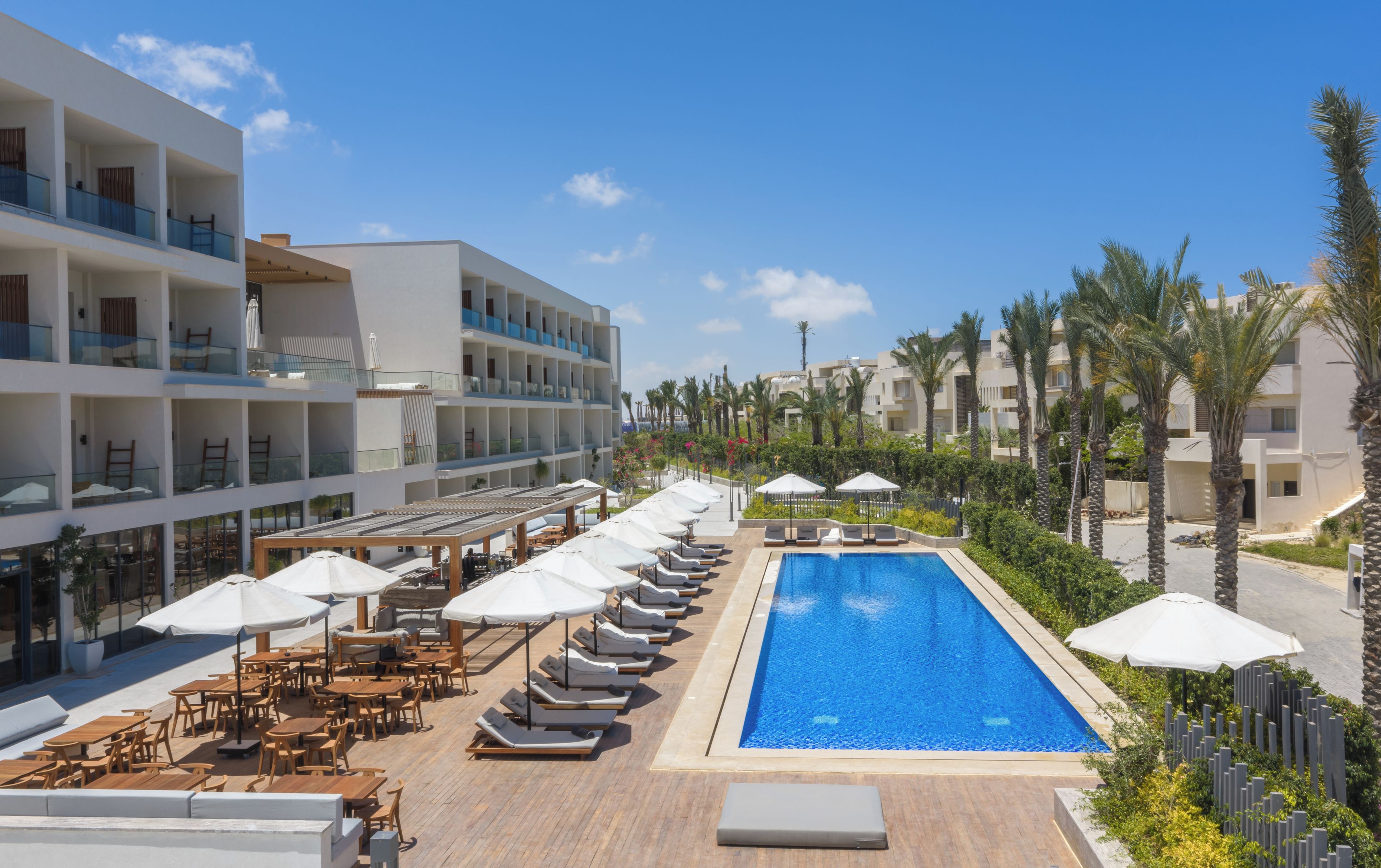 Área de piscina do resort, com espreguiçadeiras, guarda-sóis e uma piscina azul cristalina.