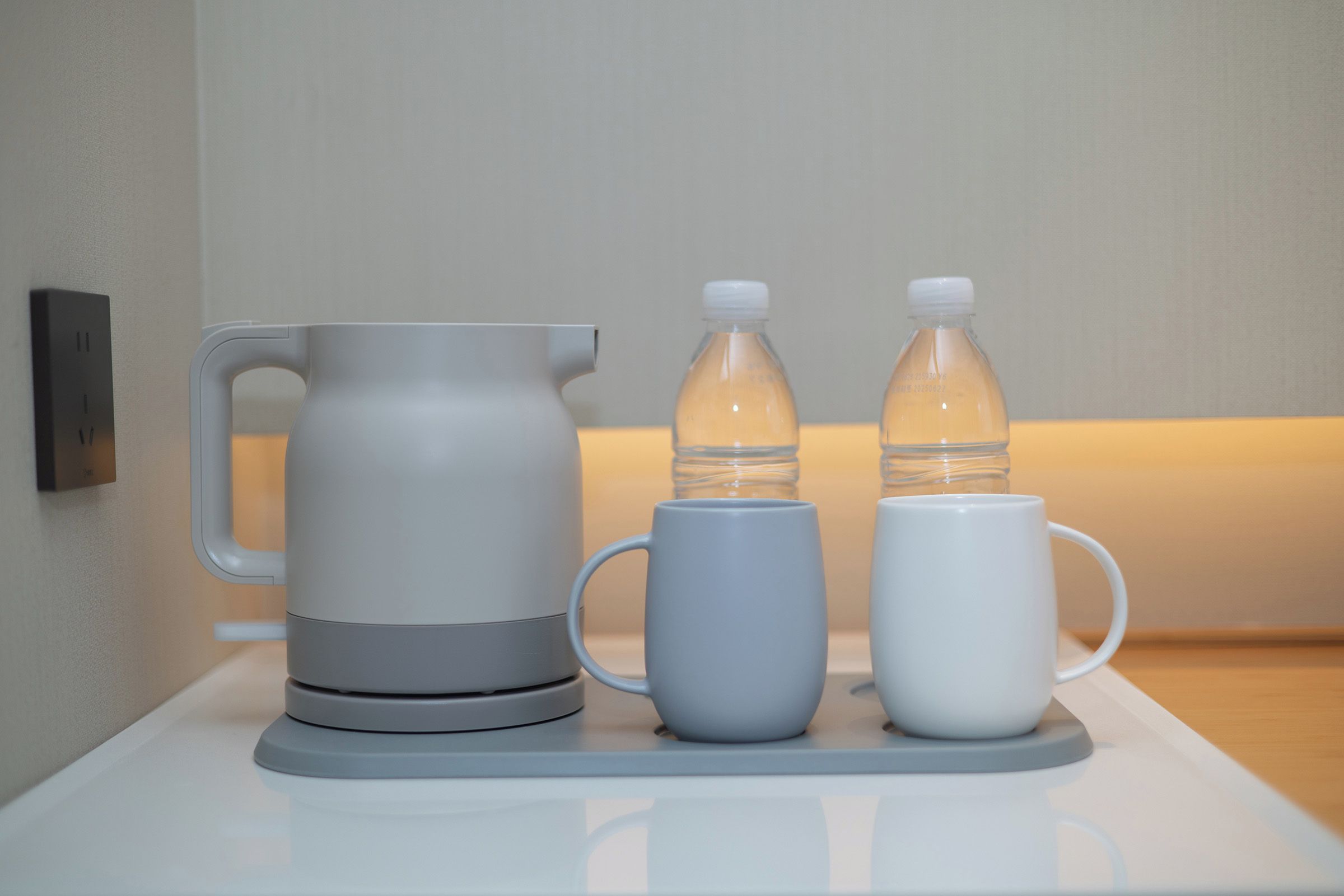Cozinha moderna com cafeteira, duas garrafas de água e duas canecas em uma bancada.
