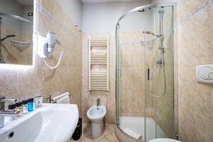 Uma casa de banho moderna com cabine de duche em vidro, lavatório assentado e bidé.