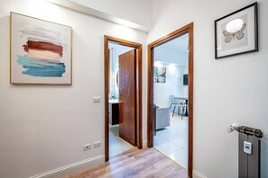 Um corredor com piso de madeira, uma pintura abstrata emoldurada e uma obra de arte com borboletas na parede.