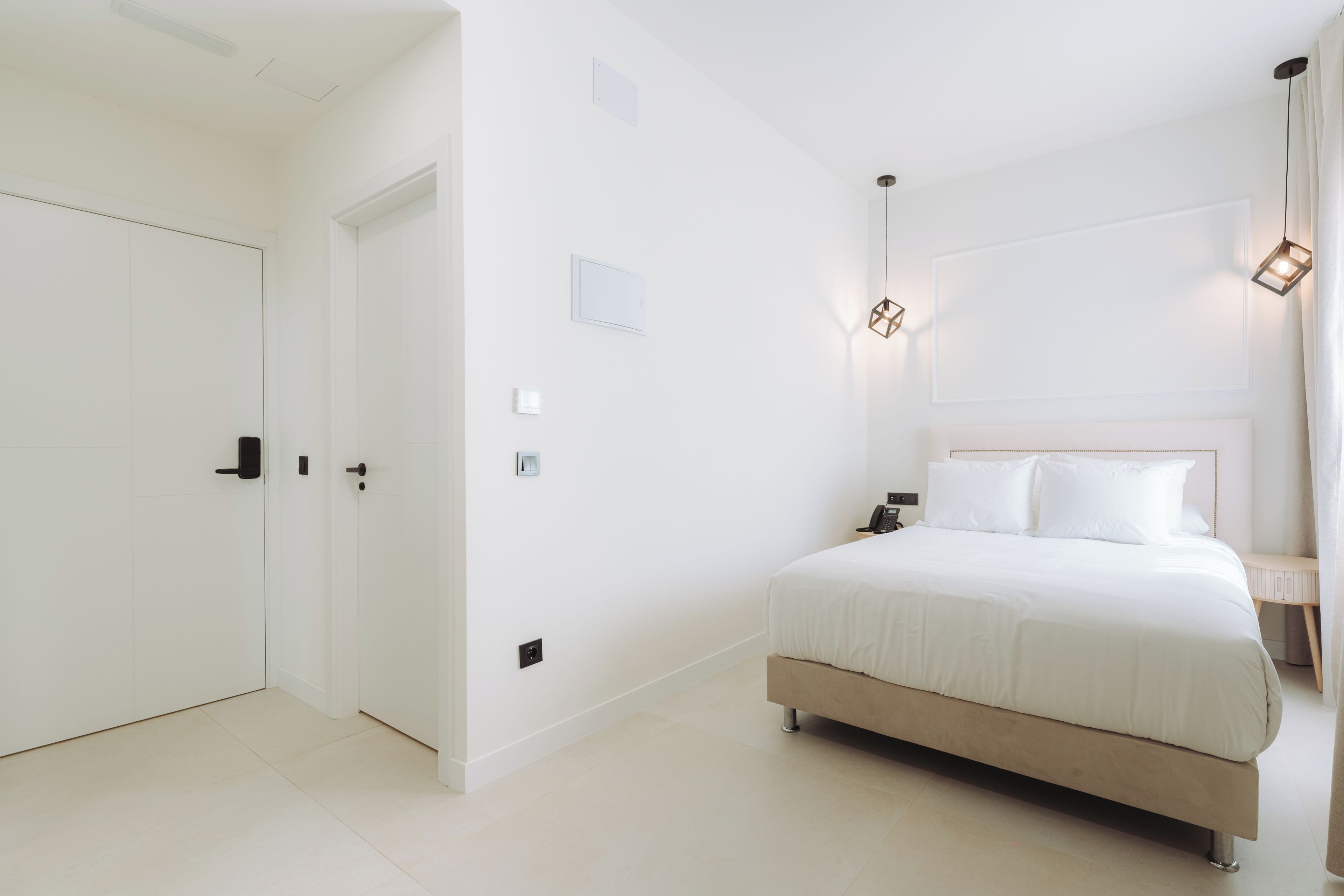 Quarto moderno com cama, mesa de cabeceira e criado-mudo.